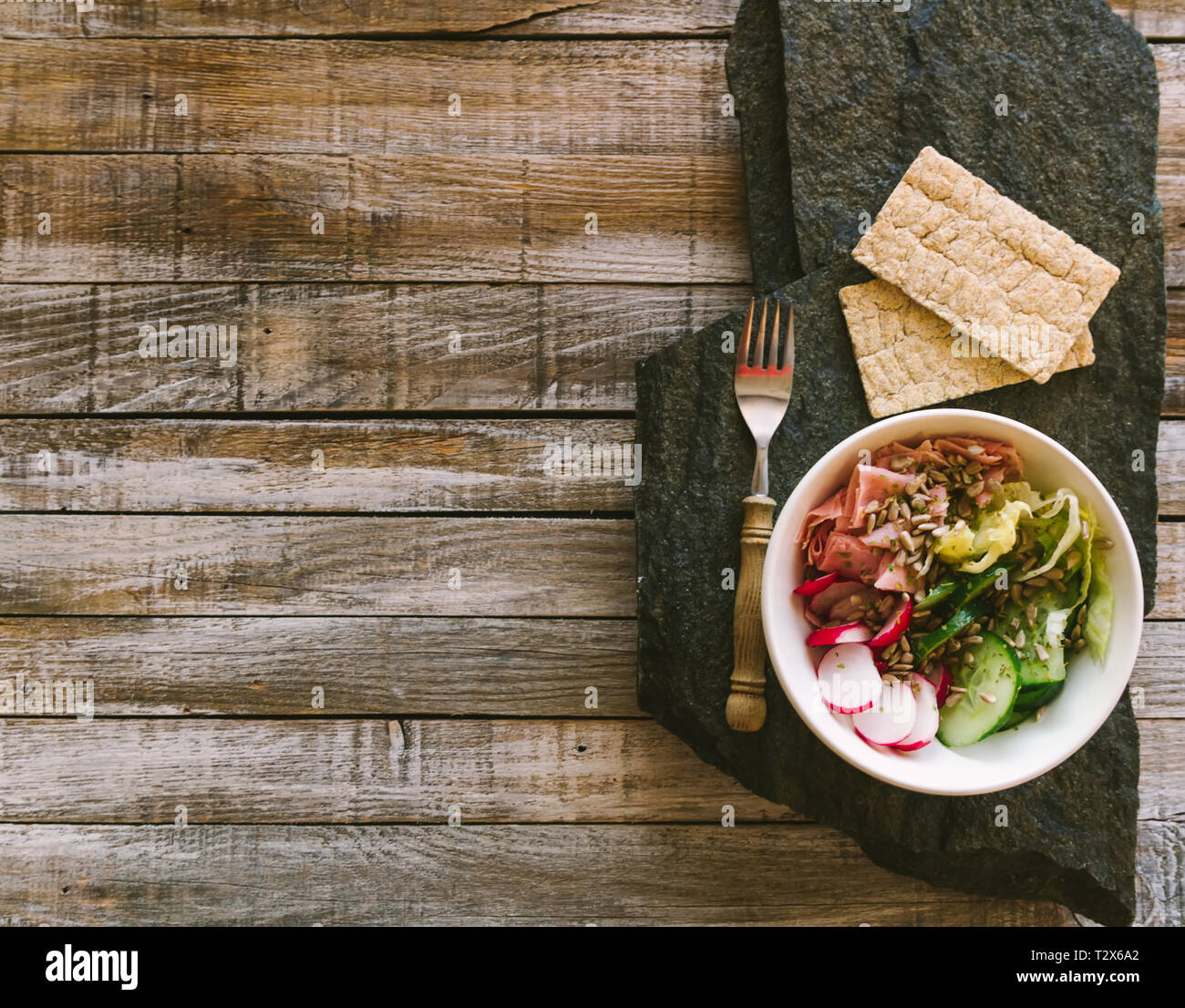 Homemade poke bowl from ham, cucumber, sunflower seed, radish, fork and ...