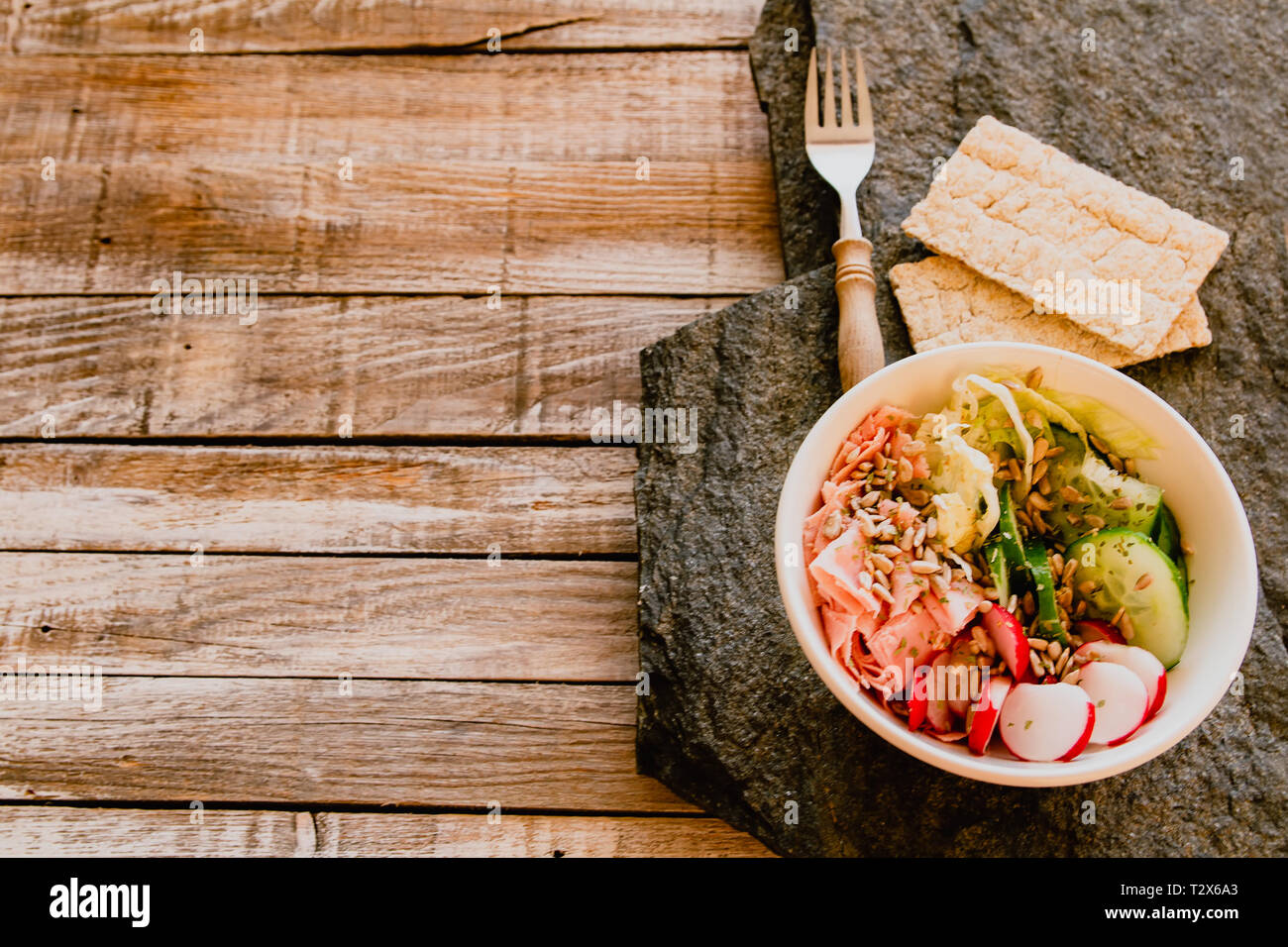 Homemade poke bowl from ham, sunflower seed, cucumber, radish, fork and ...