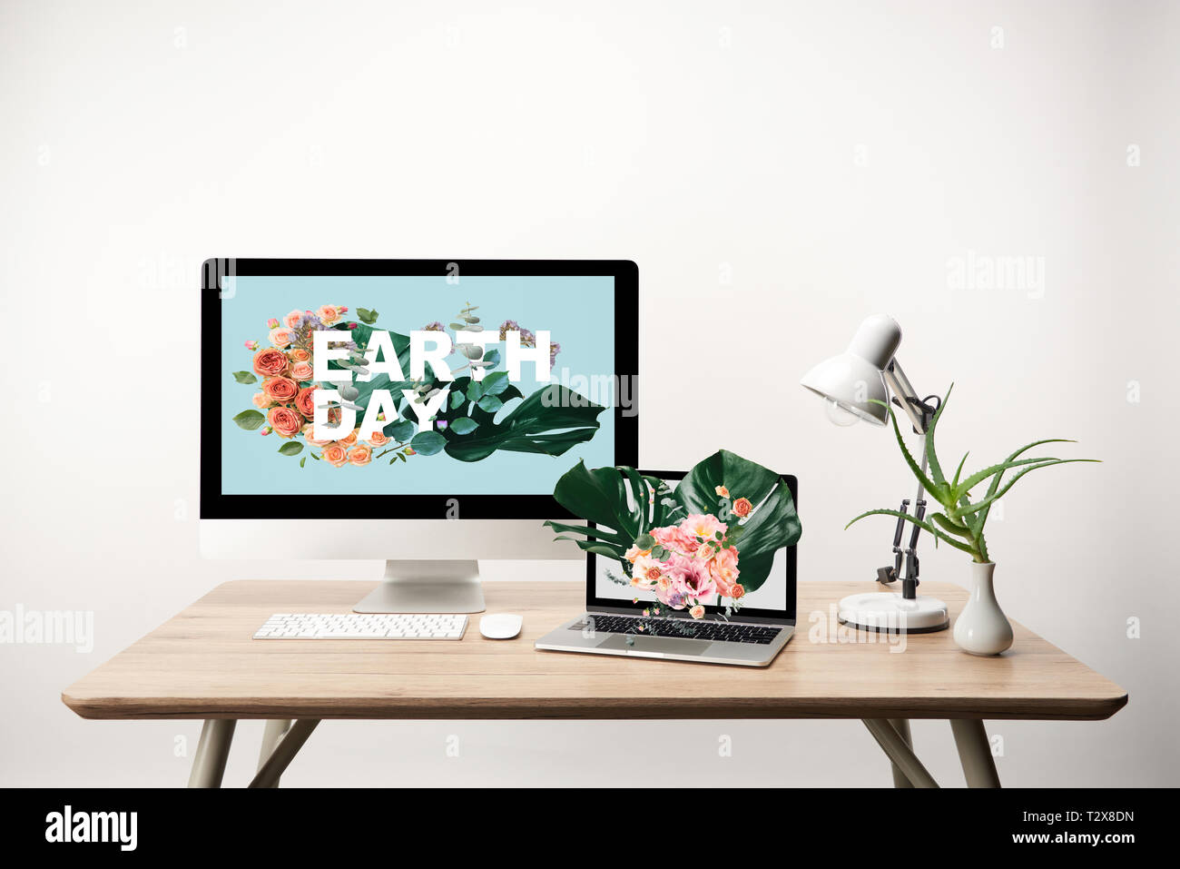 computer with earth day illustration on monitor and laptop with ...
