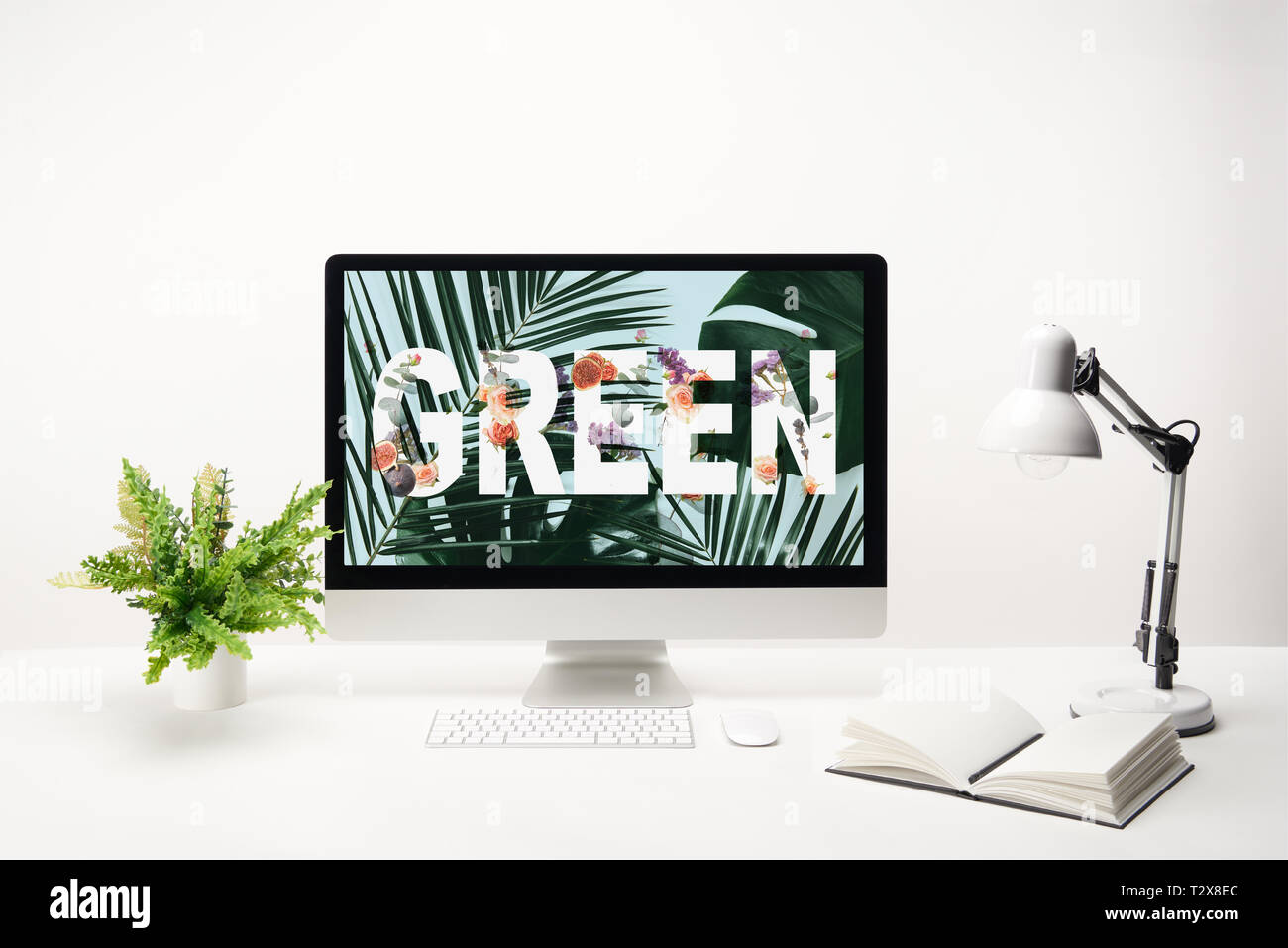 computer with green lettering and tropical leaves on monitor on desk on ...