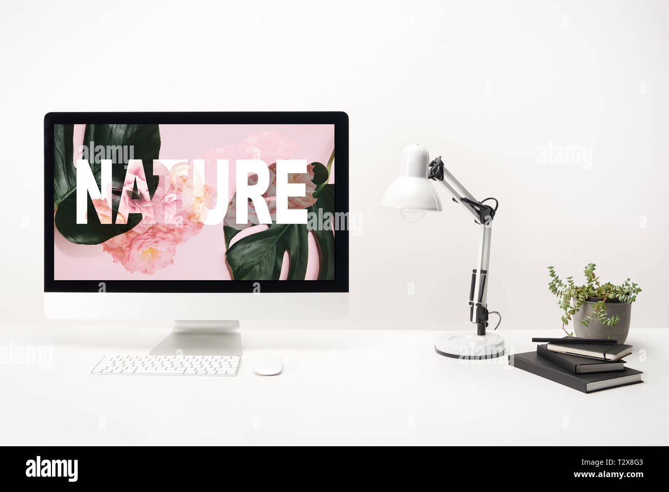 computer with green monstera leaves and roses with nature lettering on ...