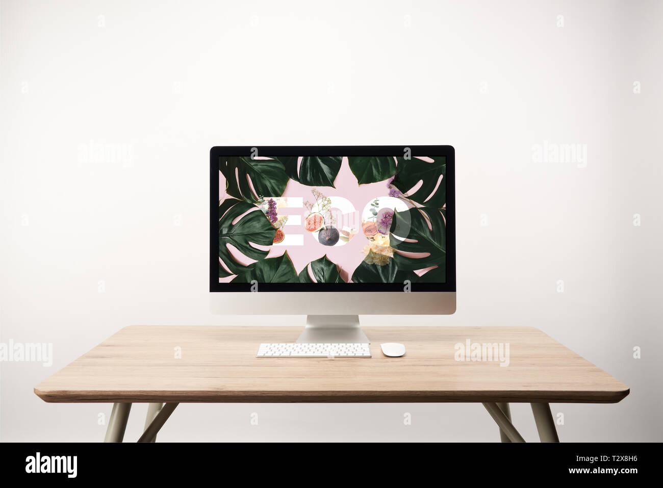 computer with green monstera leaves and eco lettering on monitor on ...