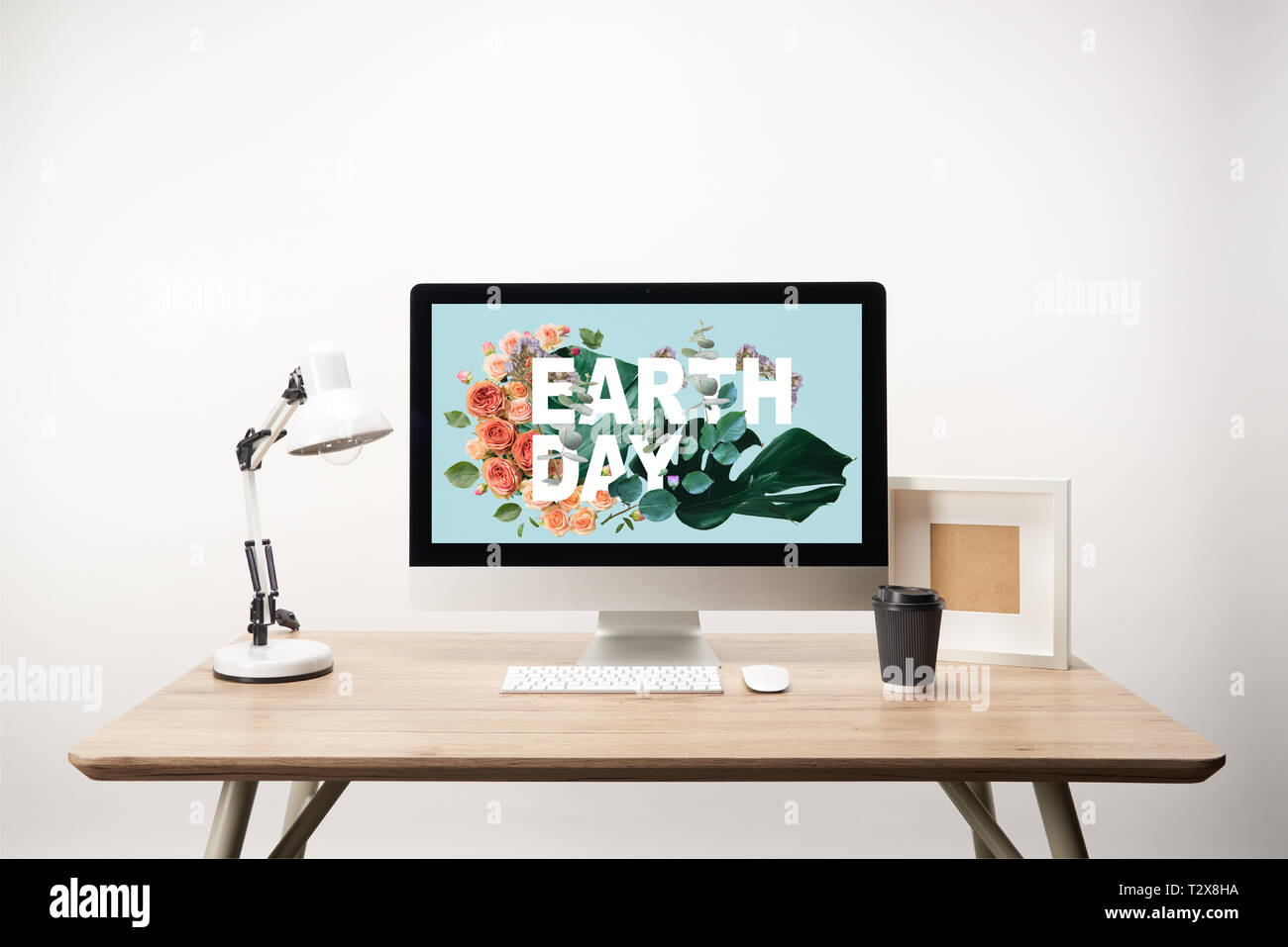 computer with green monstera leaves and flowers and earth day lettering ...