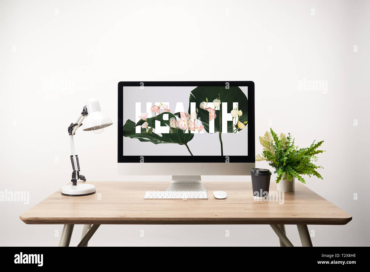 computer with green leaves and health lettering on monitor on wooden ...