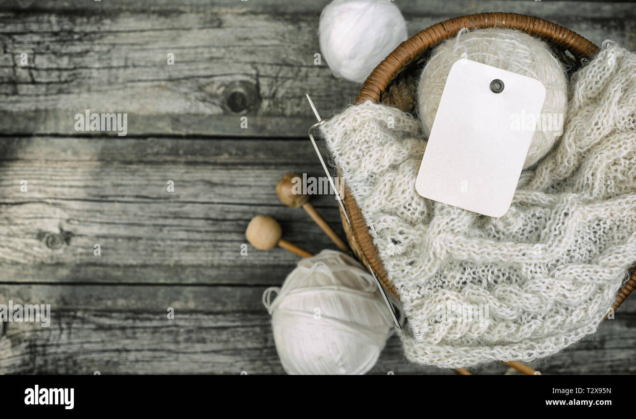 White label on wool threads roll to basket with knitting and knitting ...