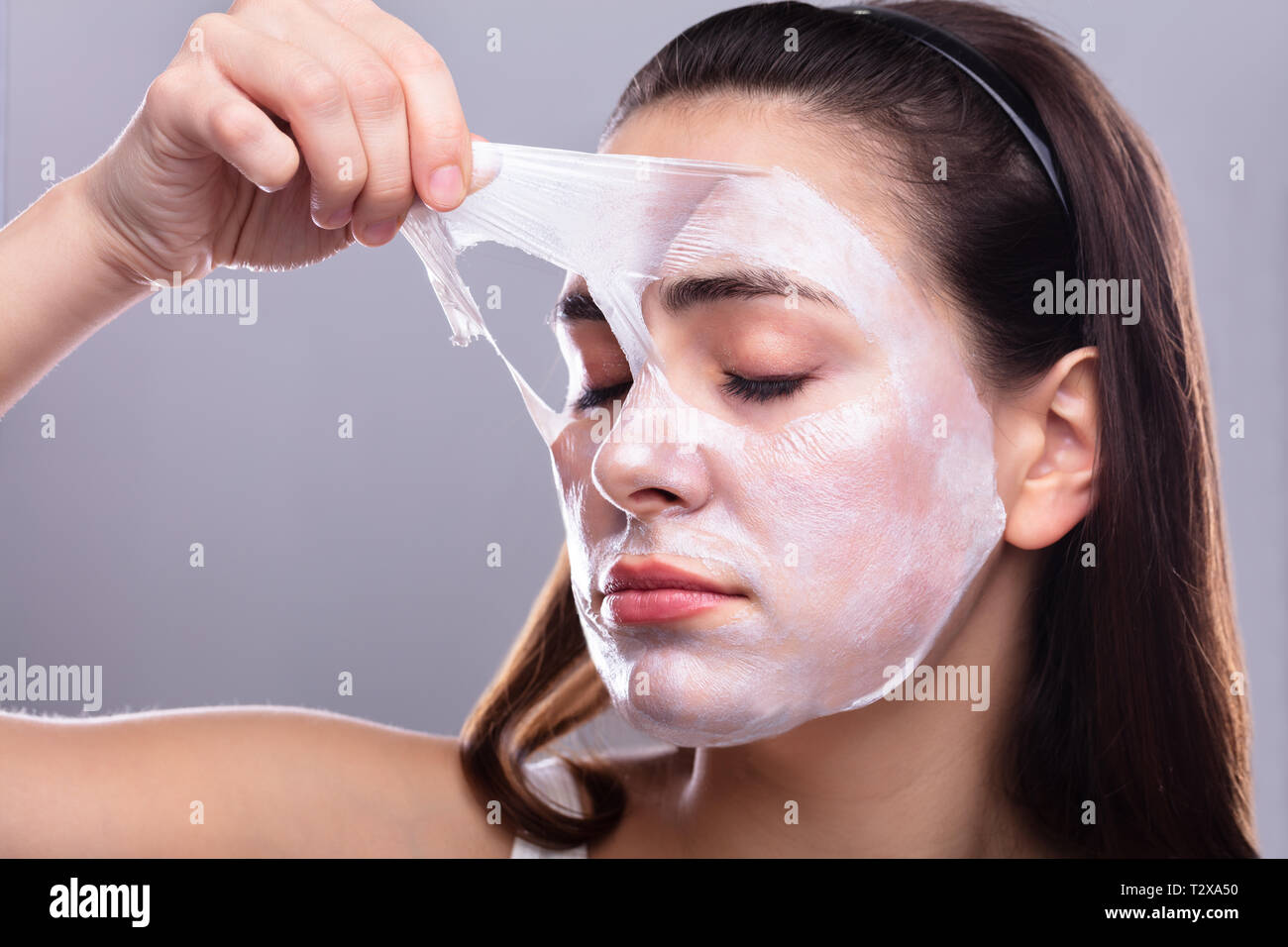 Portrait Of A Beautiful Young Woman Removing Peeling Mask From Her Face ...