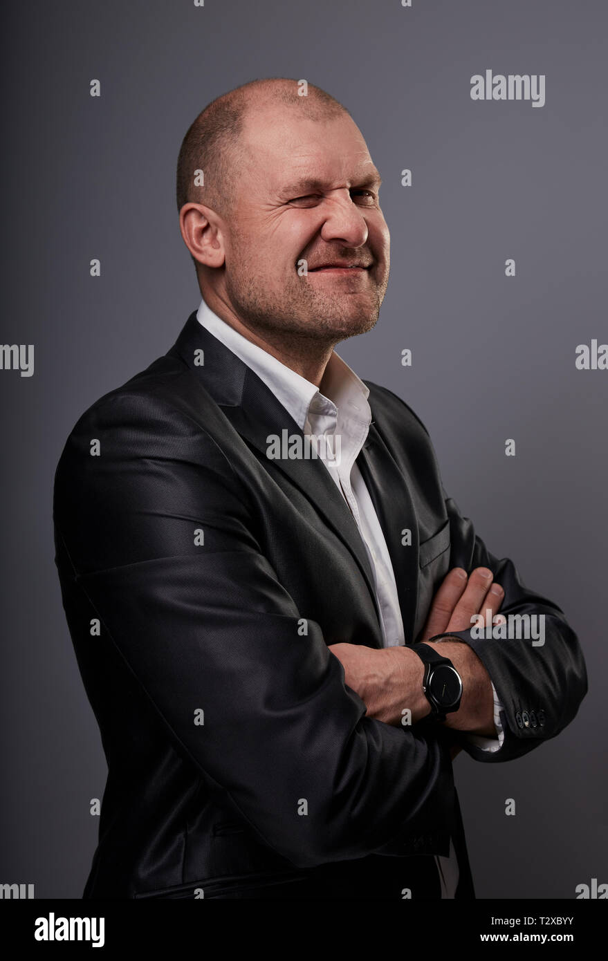 Exited bald business man winking the eye in black suit on grey ...