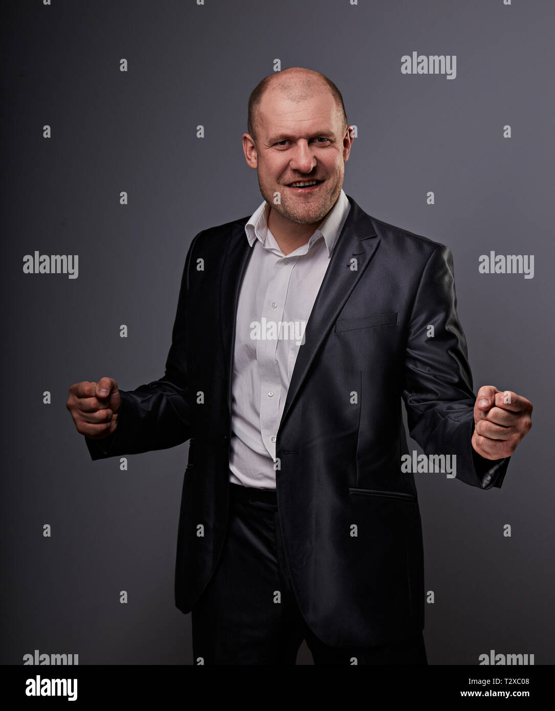 Exited bald business man in black suit showing the hands success winner ...