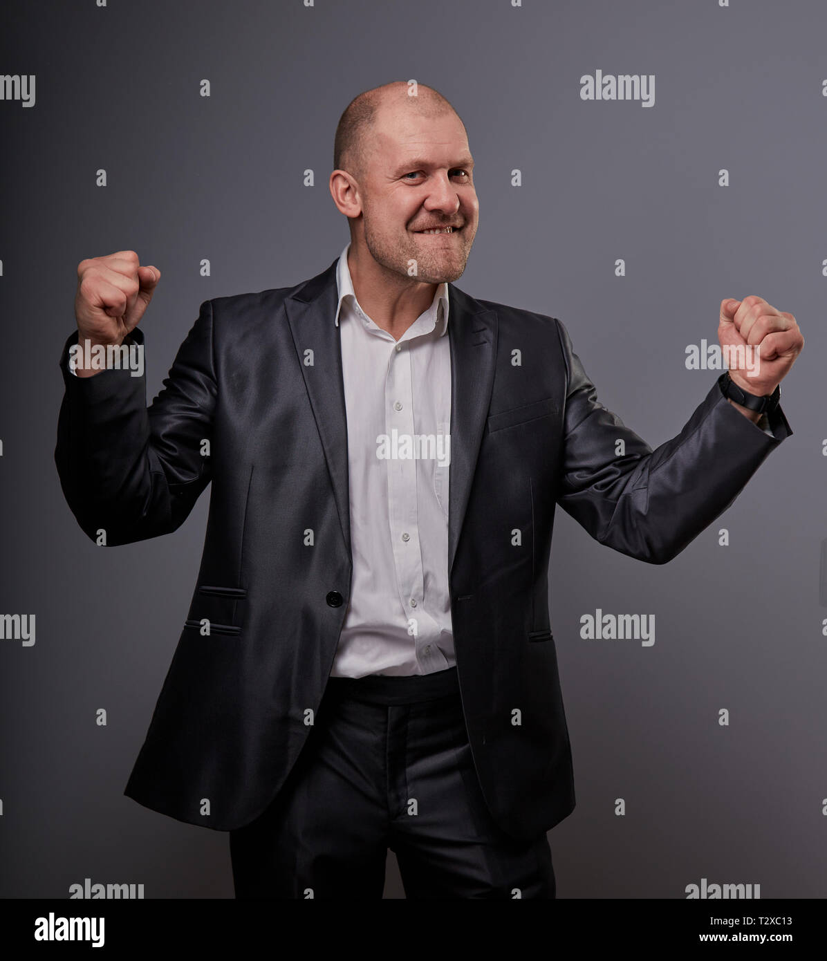 Exited bald business man in black suit showing the hands success winner ...