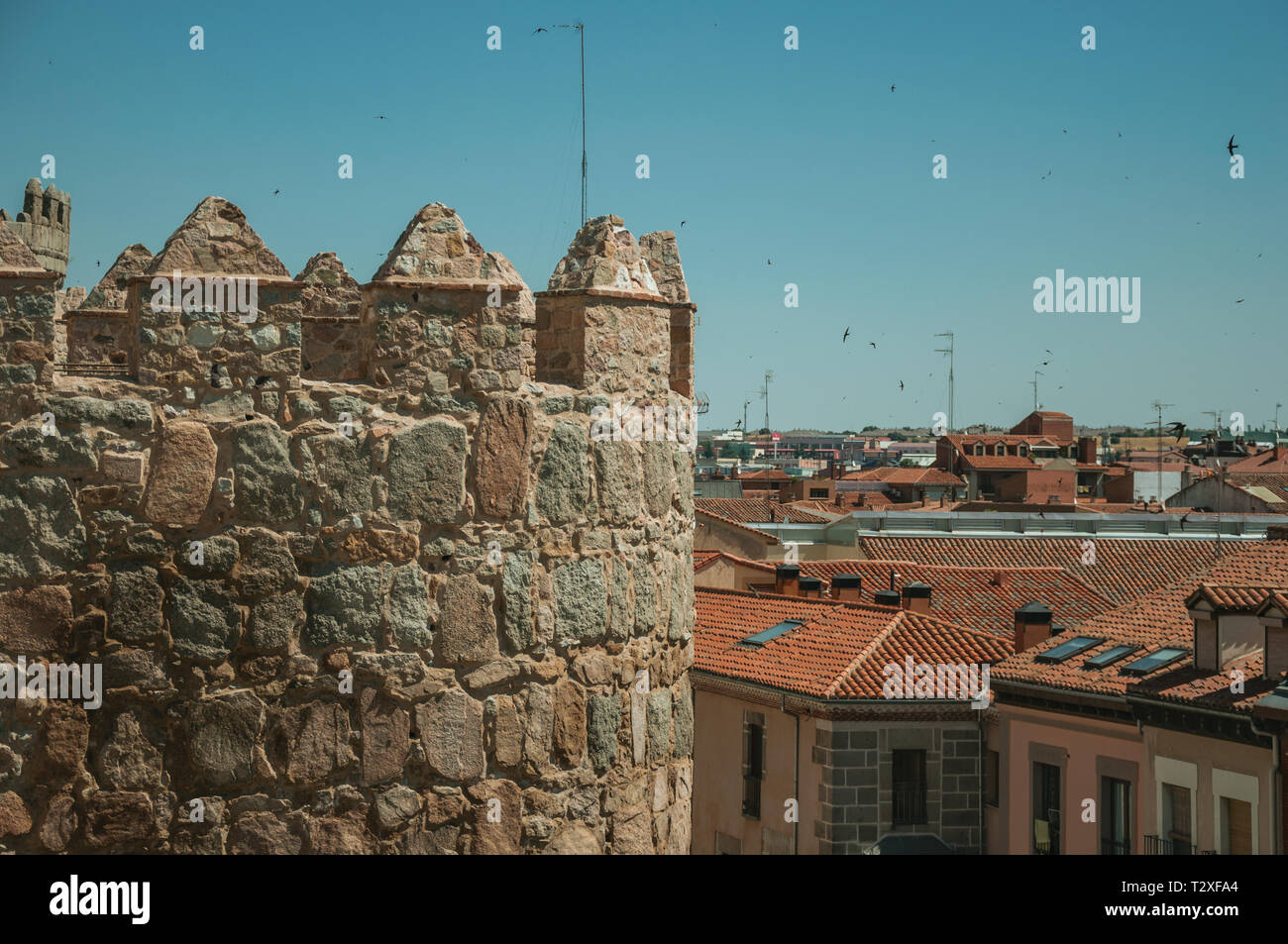 Battlement with merlons and crenels over stone tower and rooftops on ...