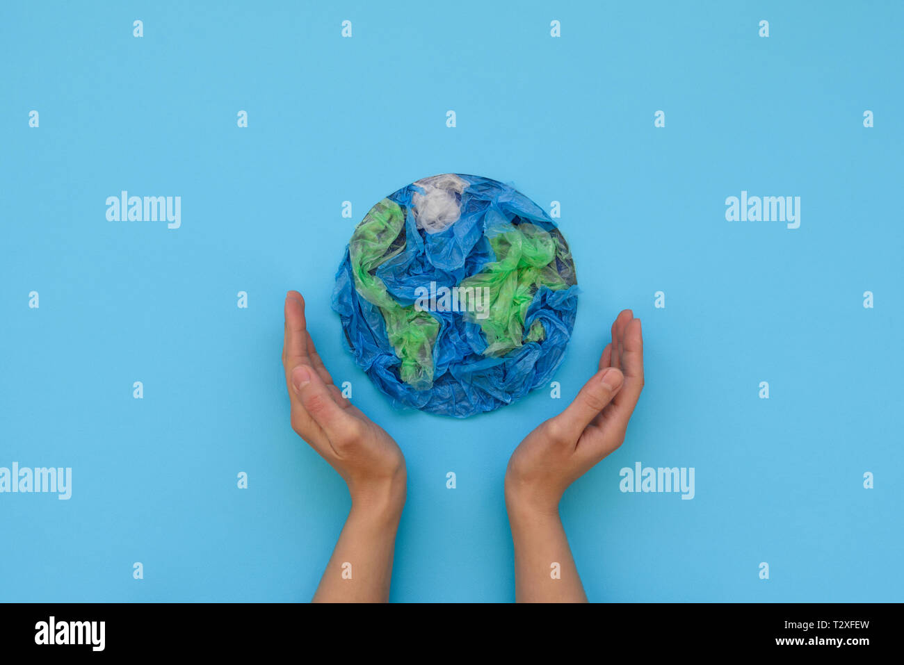 Hands holding planet Earth made from plastic disposable packages on ...
