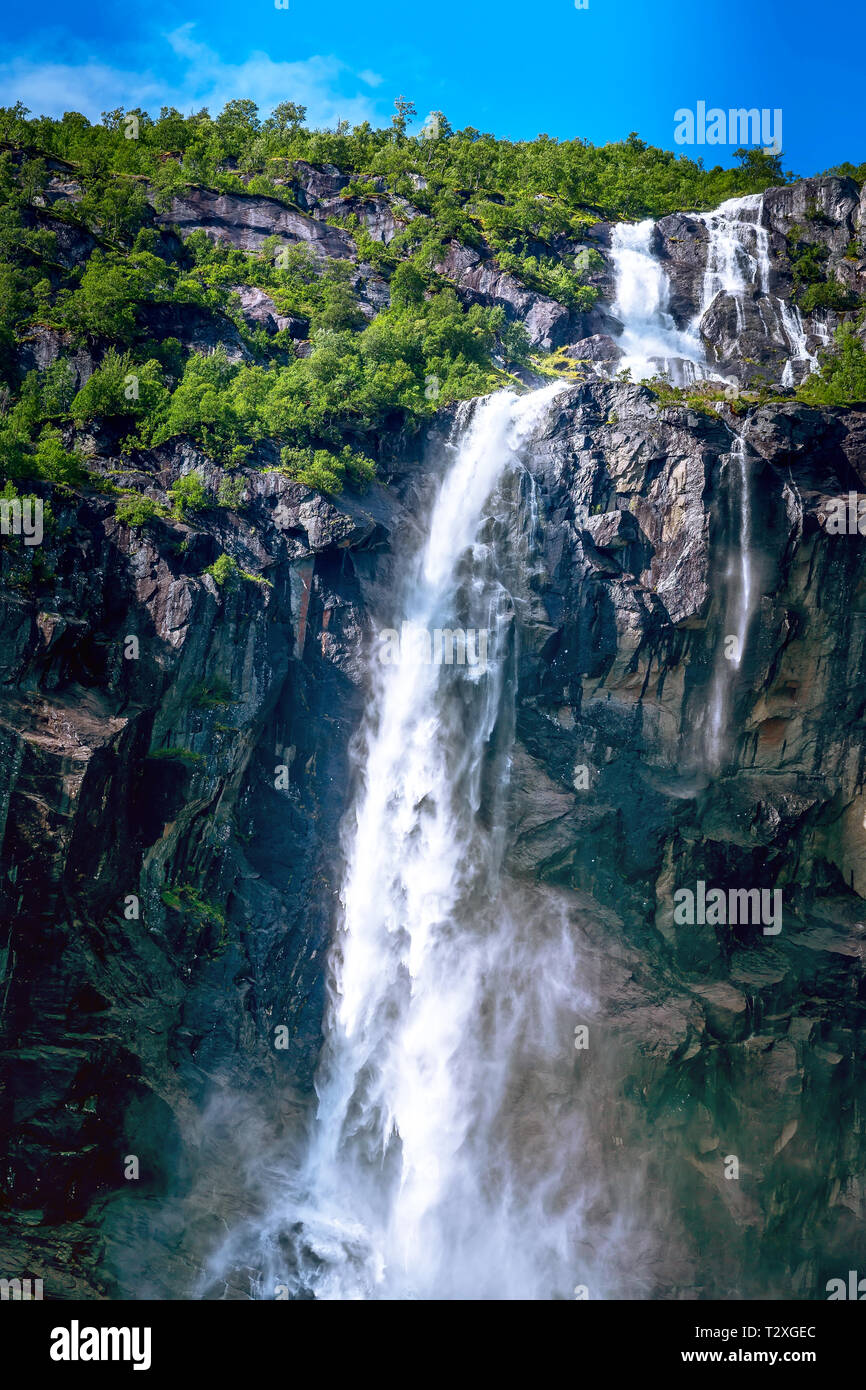 Waterfall and green trees on the way to Briksdal or Briksdalsbreen ...