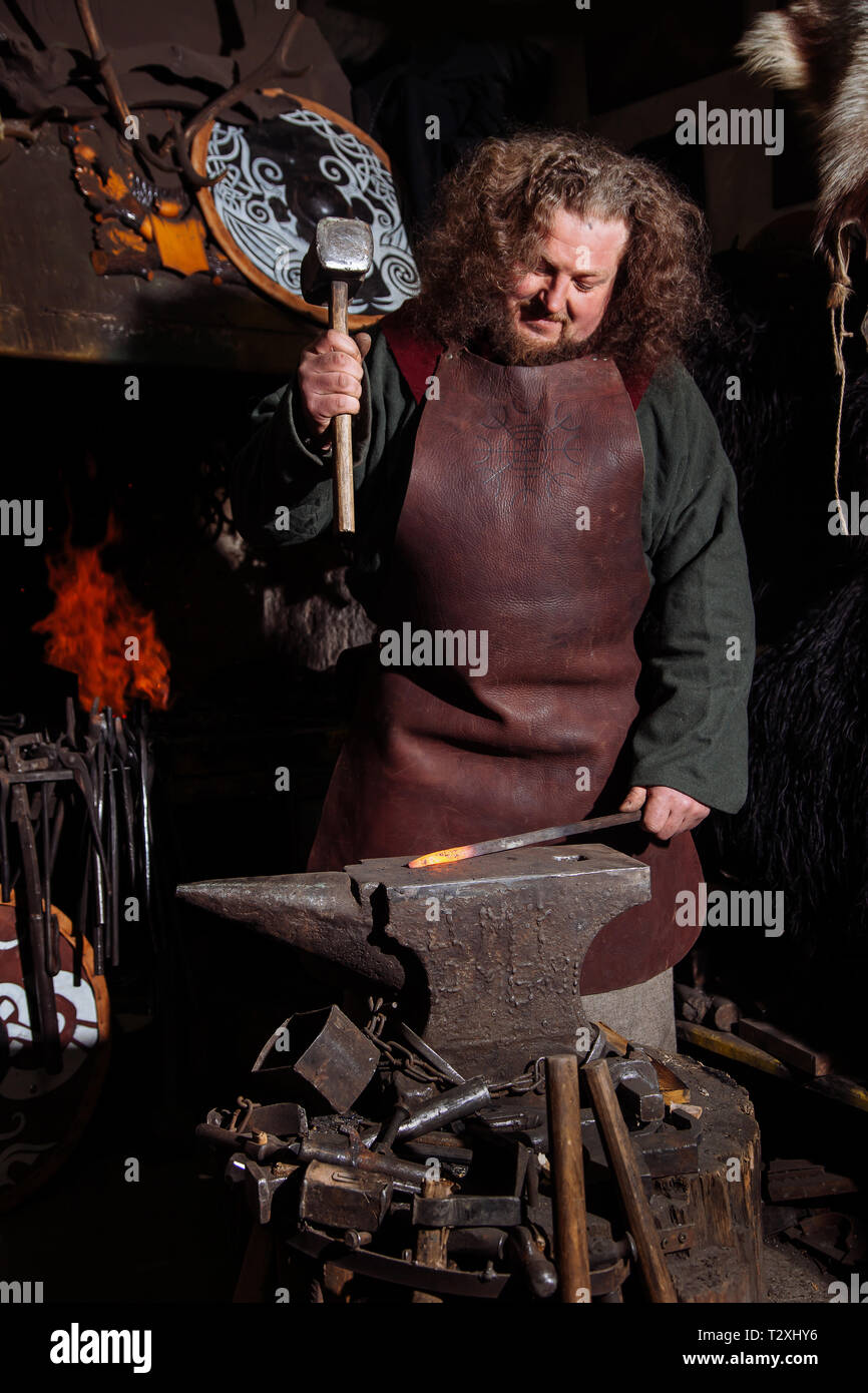 Viking forges weapons and swords in the smithy. A man in a warrior's ...