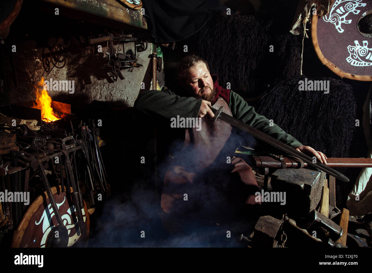 Viking forges weapons and swords in the smithy. A man in a warrior's ...