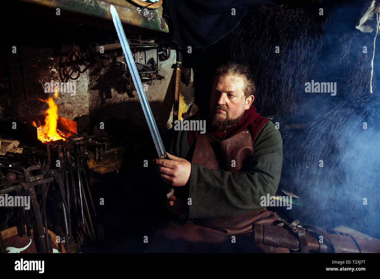 Viking forges weapons and swords in the smithy. A man in a warrior's ...