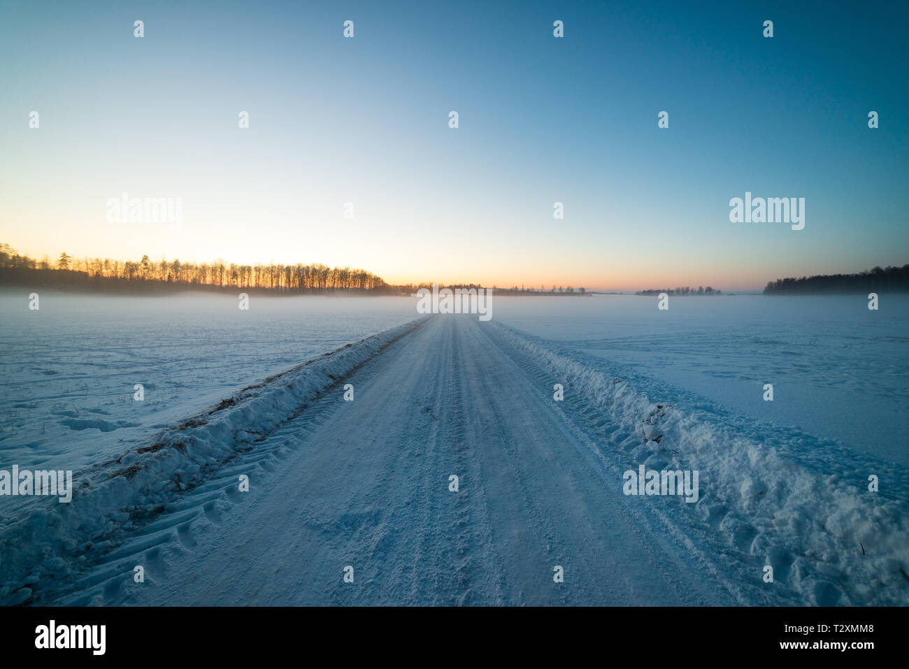 snowy winter road covered in ice and snow in forest woth blue sky Stock ...
