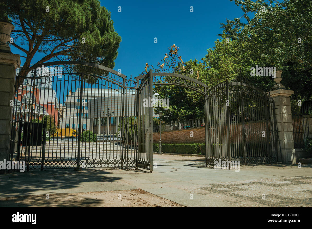 Open gateway and wrought iron fence with gold decoration on garden in ...