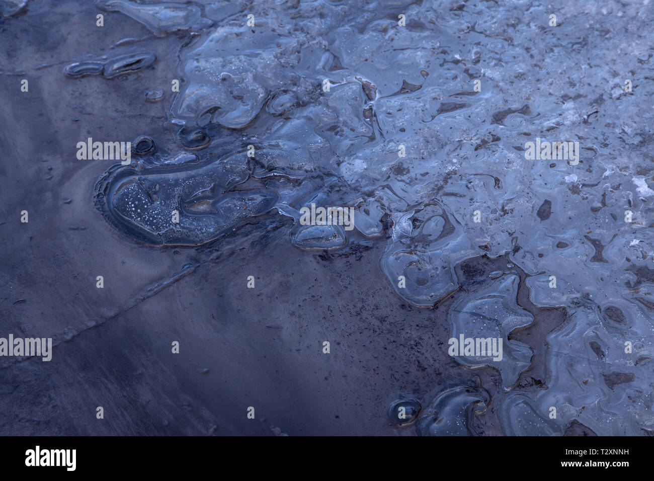 Tidal waters wash glacial silt over the melting ice along the shore of ...