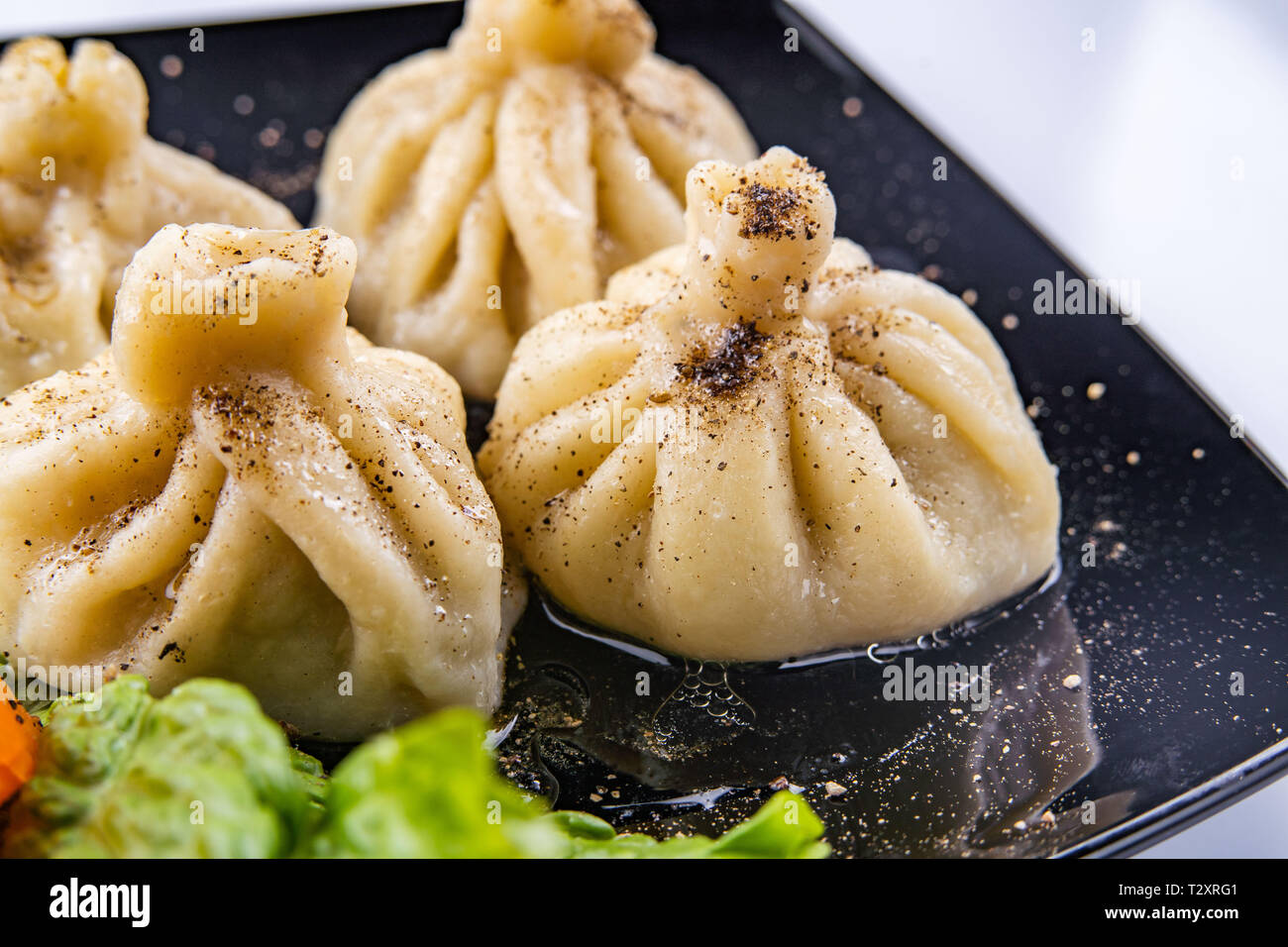 Georgian dumplings Khinkali with meat and red papper, on black plate ...