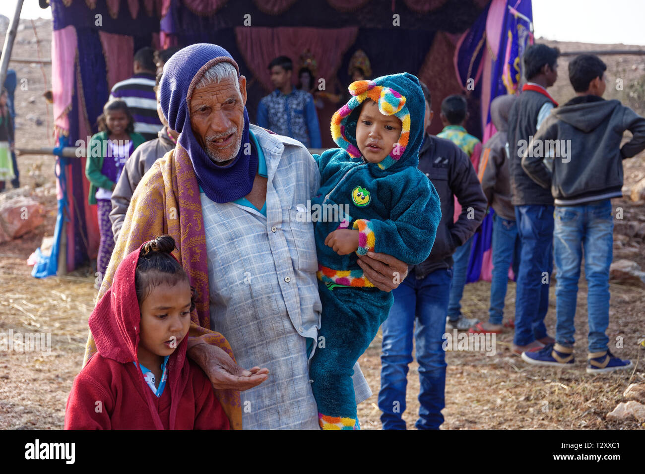 Old man carrying two children in a rural gathering Stock Photo - Alamy