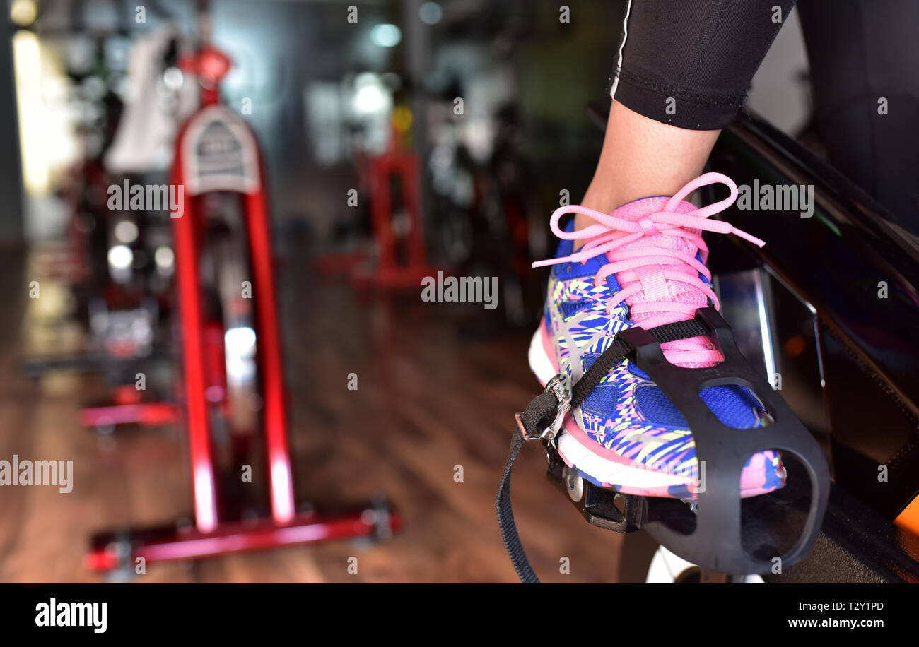 Running shoe of the sportive girl cycling on fitness spinning bike ...