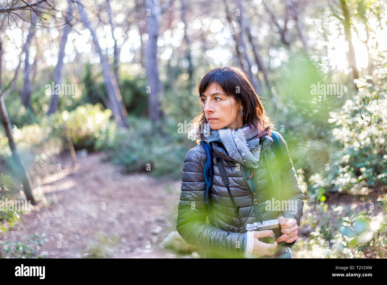 Front view of a backpacker looking away while standing into the forest ...