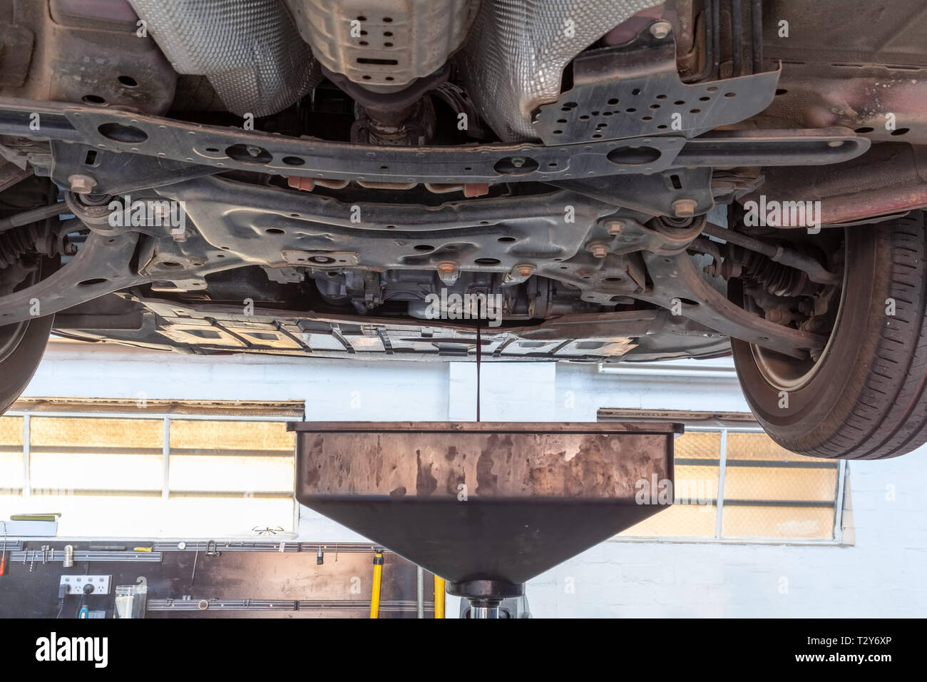 Draining of used engine oil from car lifted on hydraulic lift in ...