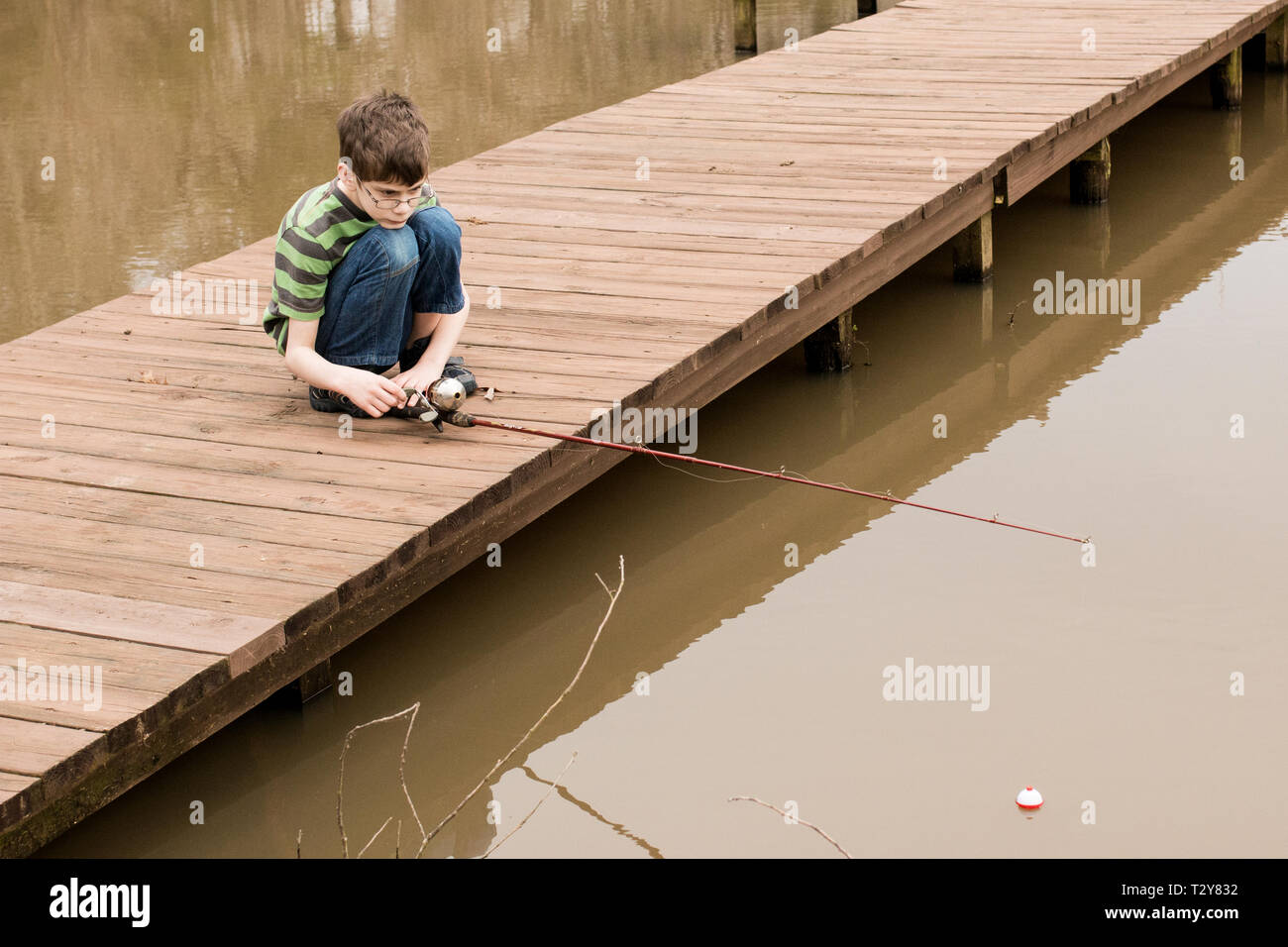 An eleven-year-old boy fishing on a dock in Madison, Mississippi, USA ...