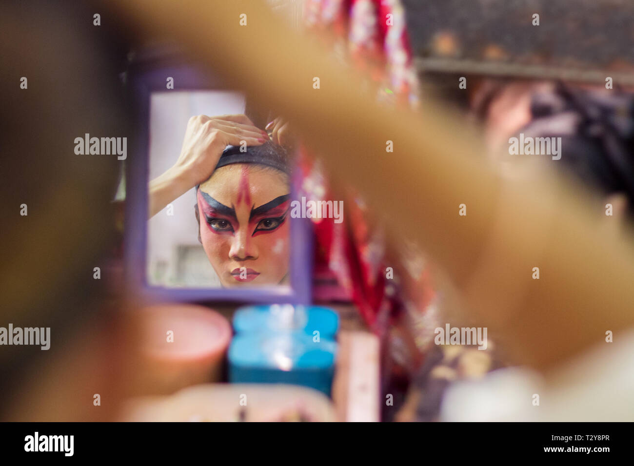 performer from a traditional Chinese opera show putting on makeup at ...