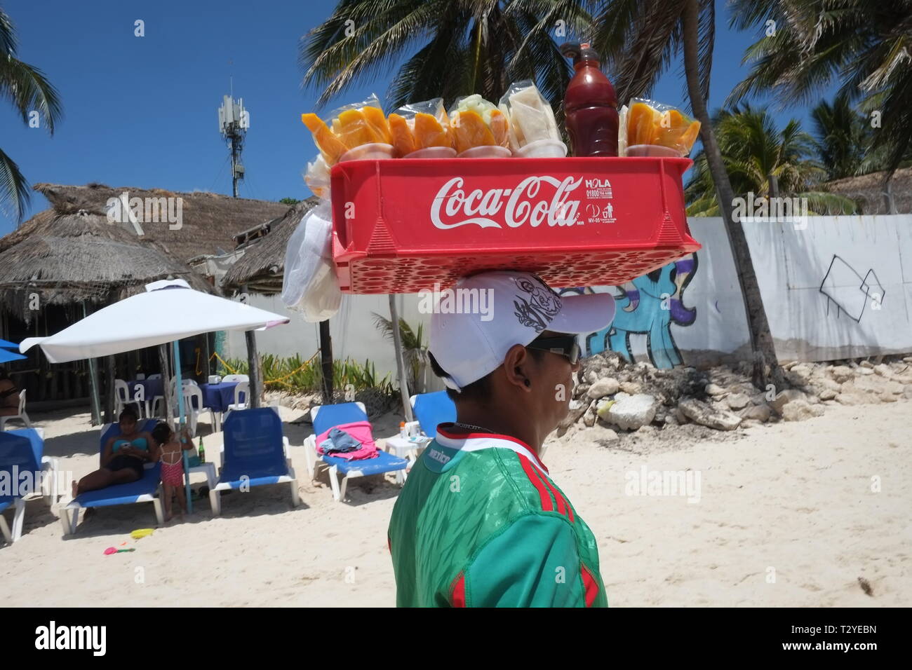 Beach vendor selling mango and pineapple in a Coca Cola box on top of ...