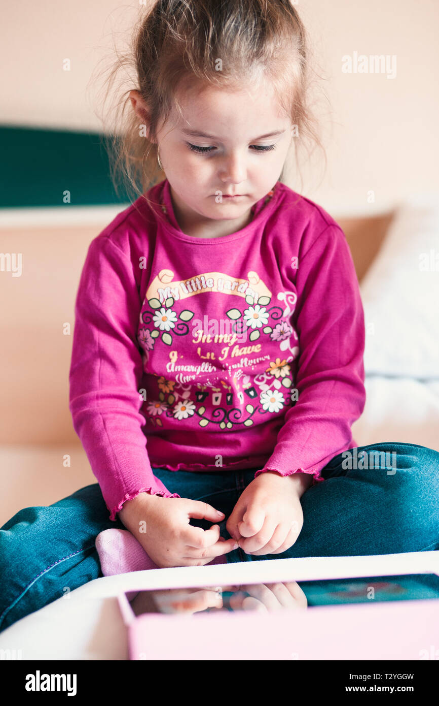 Little girl watching a animated movie for kids on tablet, sitting in ...