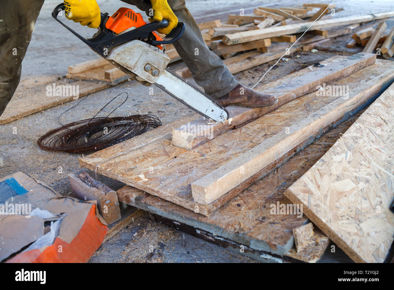 A man using a chainsaw saws a wooden beam Stock Photo - Alamy