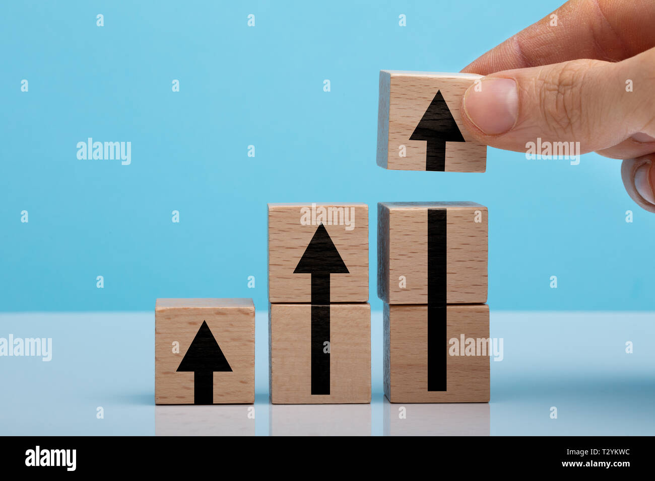 Man's Hand Arrow Sign Wooden Block On White Table Against Blue Backdrop ...