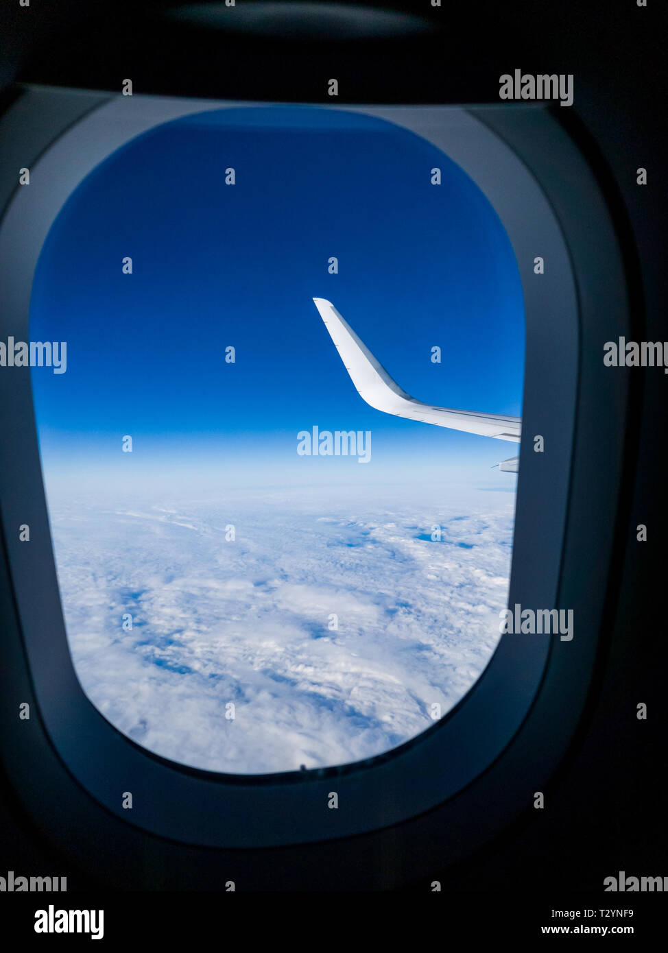Image of view outside a flying airplane with wing, blue sky and earth ...