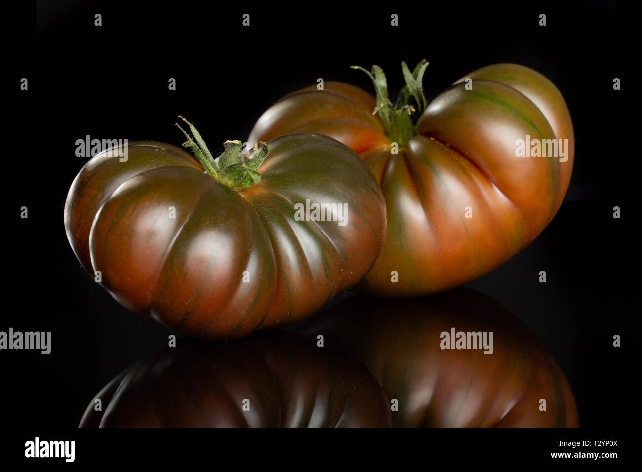 Group of two whole fresh tomato primora isolated on black glass Stock ...