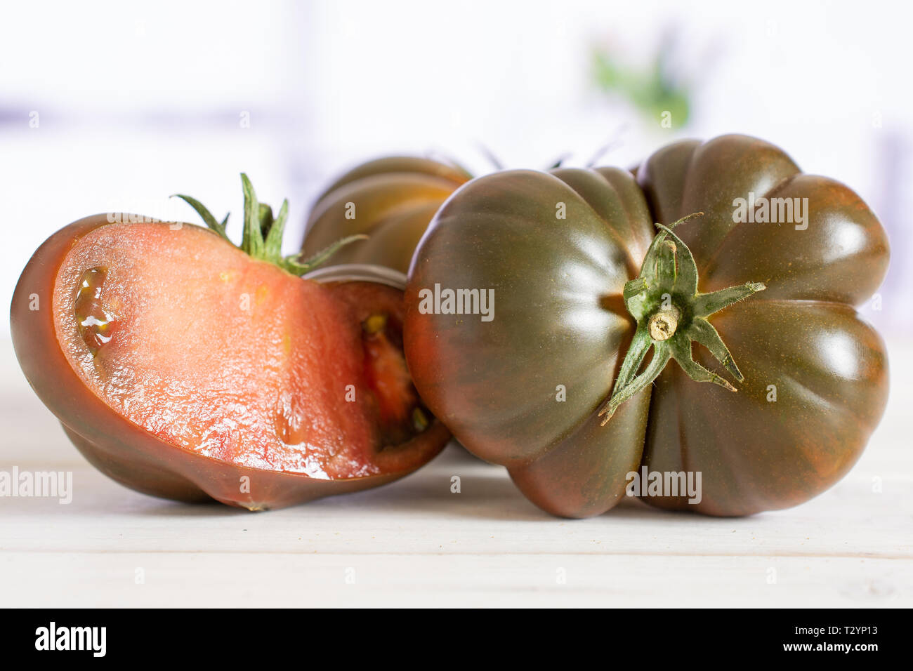 Group of two whole one half of dark fresh tomato primora in a white ...