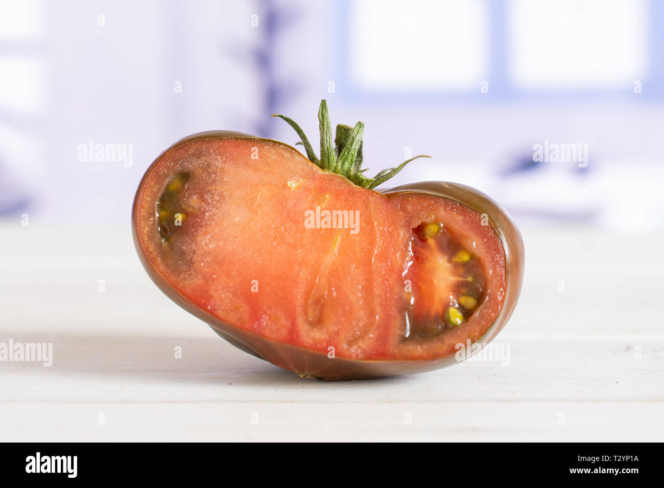 One whole fresh tomato primora with blue window in a white kitchen ...