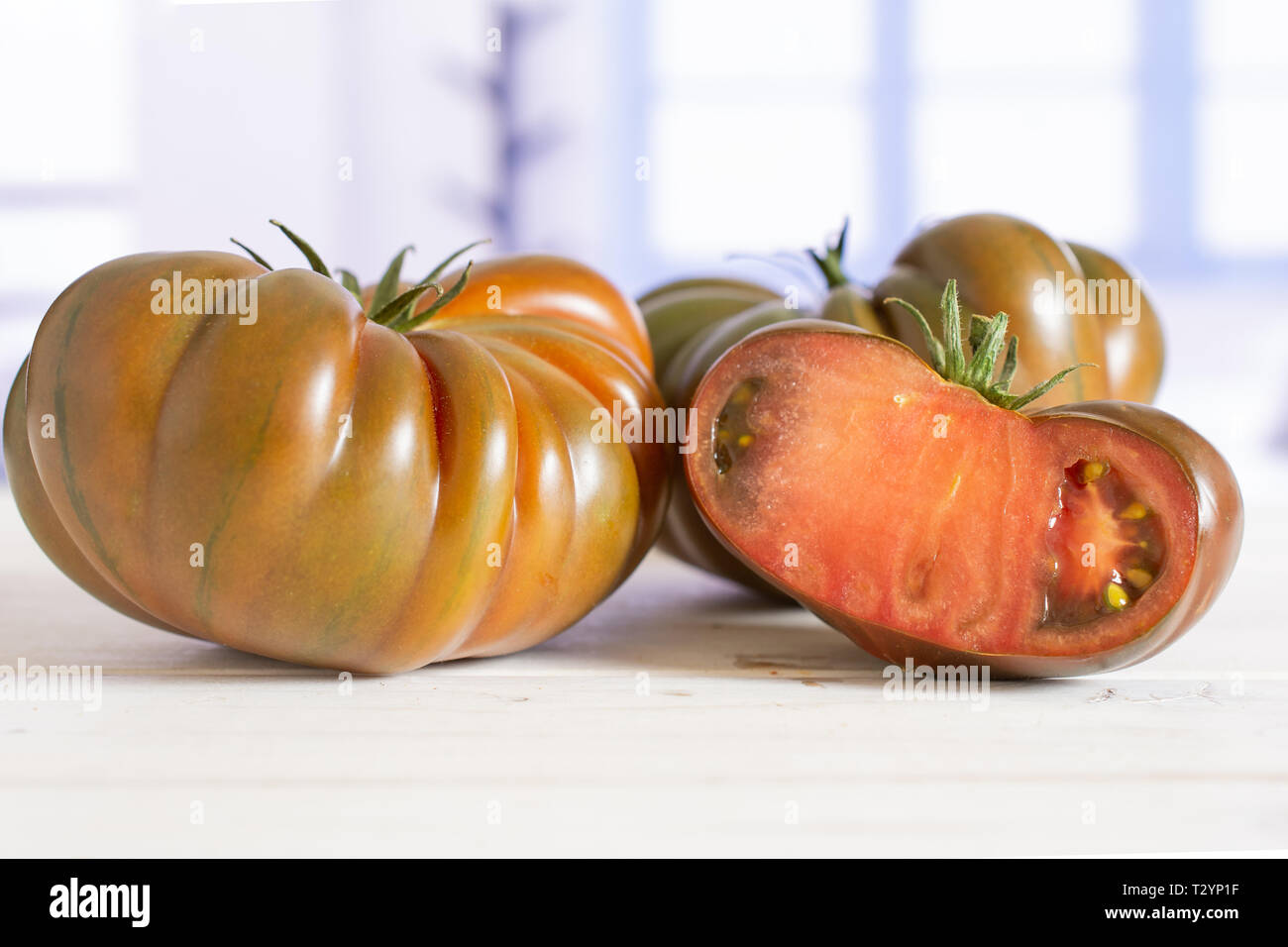Group of two whole one half of fresh tomato primora with blue window in ...
