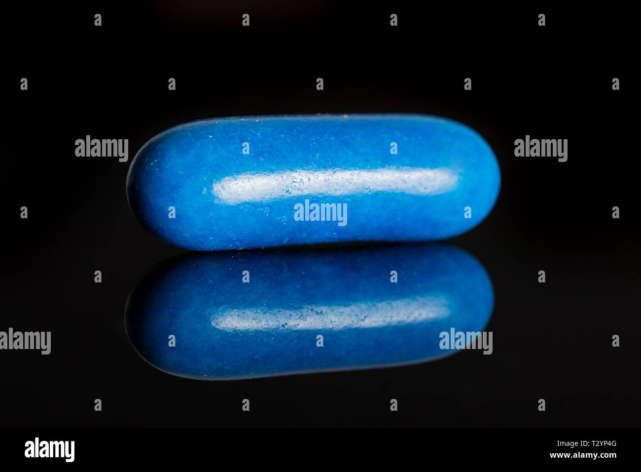 One whole blue sweet licorice comfit isolated on black glass Stock ...