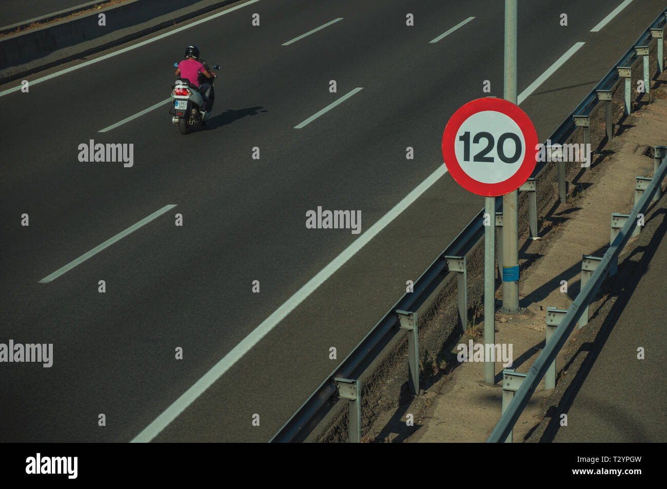 Lonely motorcycle passing through highway and SPEED LIMIT signpost in ...