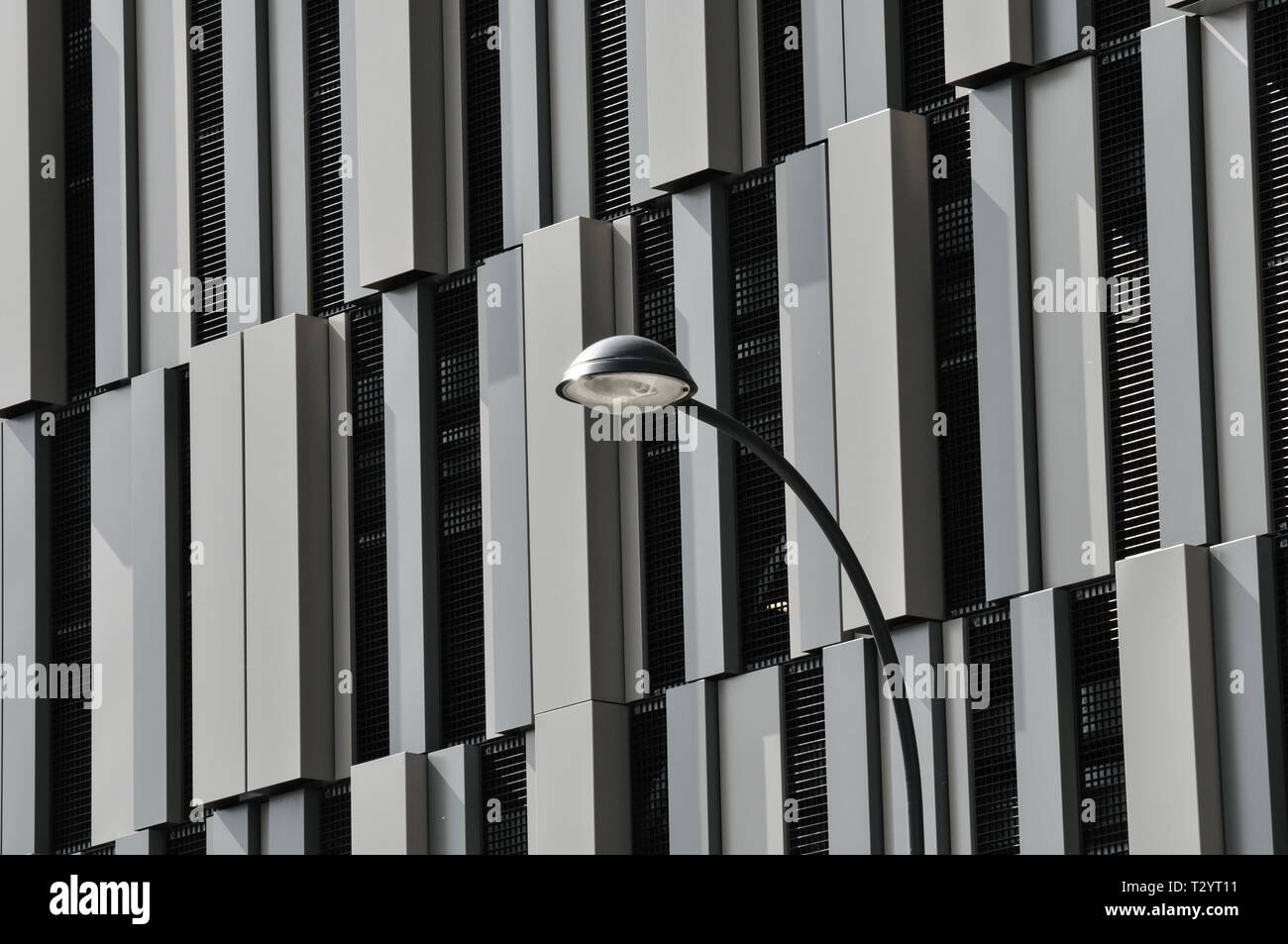 Curving street lamp contrasting with angular blocks of architecture ...