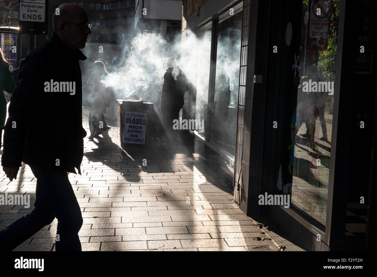 Man vaping by a newspaper stand on a street corner in Sheffield, with ...
