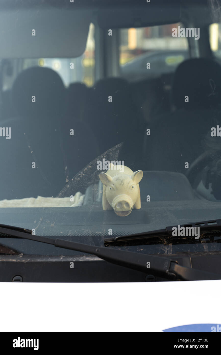 Cute fat pig toy behind a car's windshield window - Sunny reflection ...