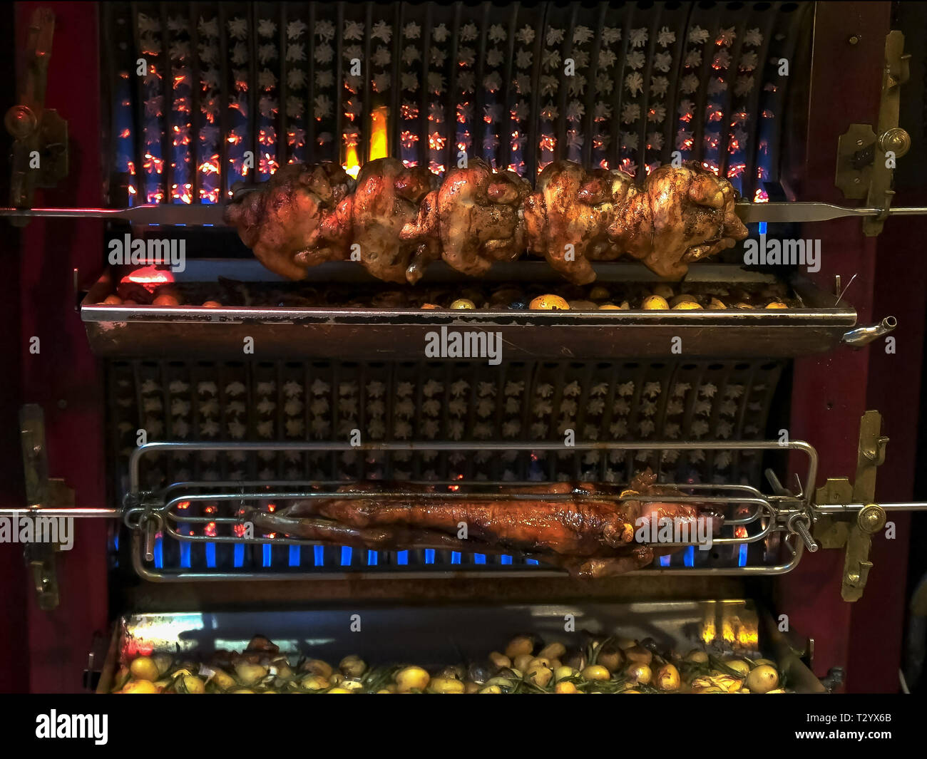 a suckling pig, chickens and vegetables are roasted on a rotisserie at ...