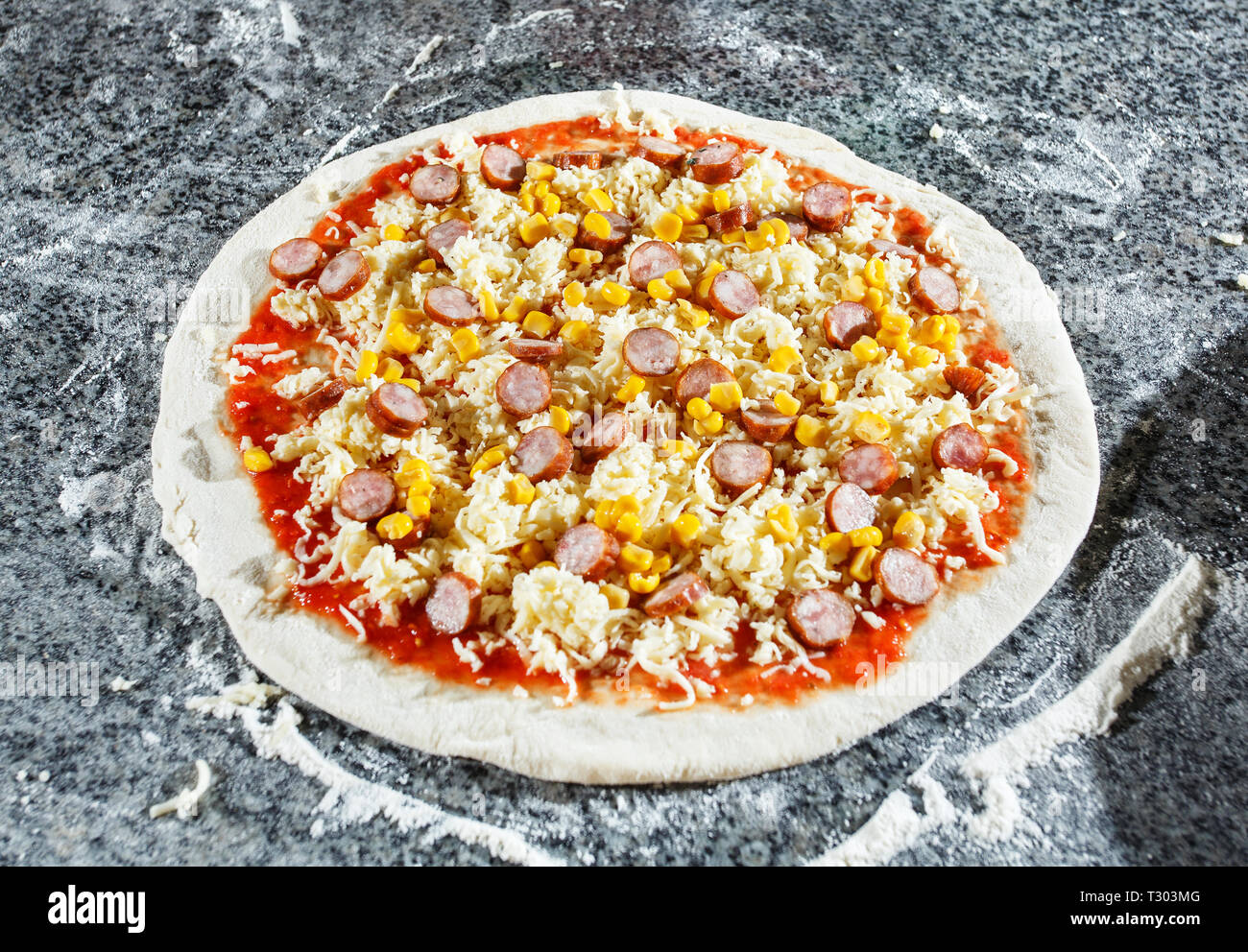 Cooking pizza in the cafe. Pizza with sausage, cheese and corn before ...