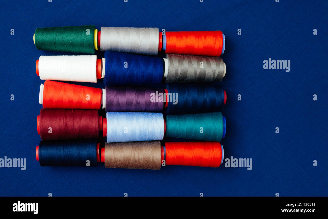 A set of threads of different colors on the blue backgtound. Many ...