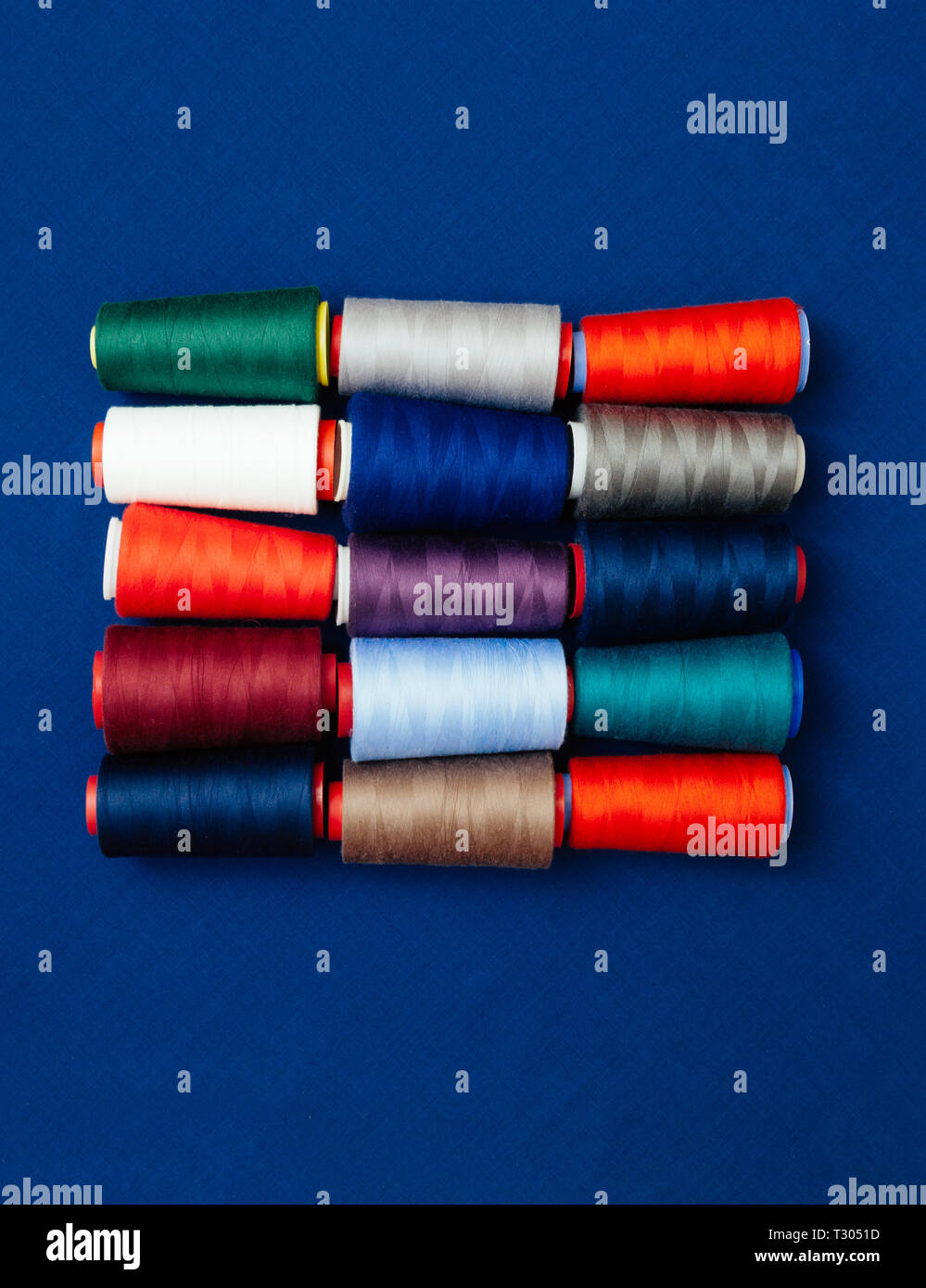 A set of threads of different colors on the blue backgtound. Many ...