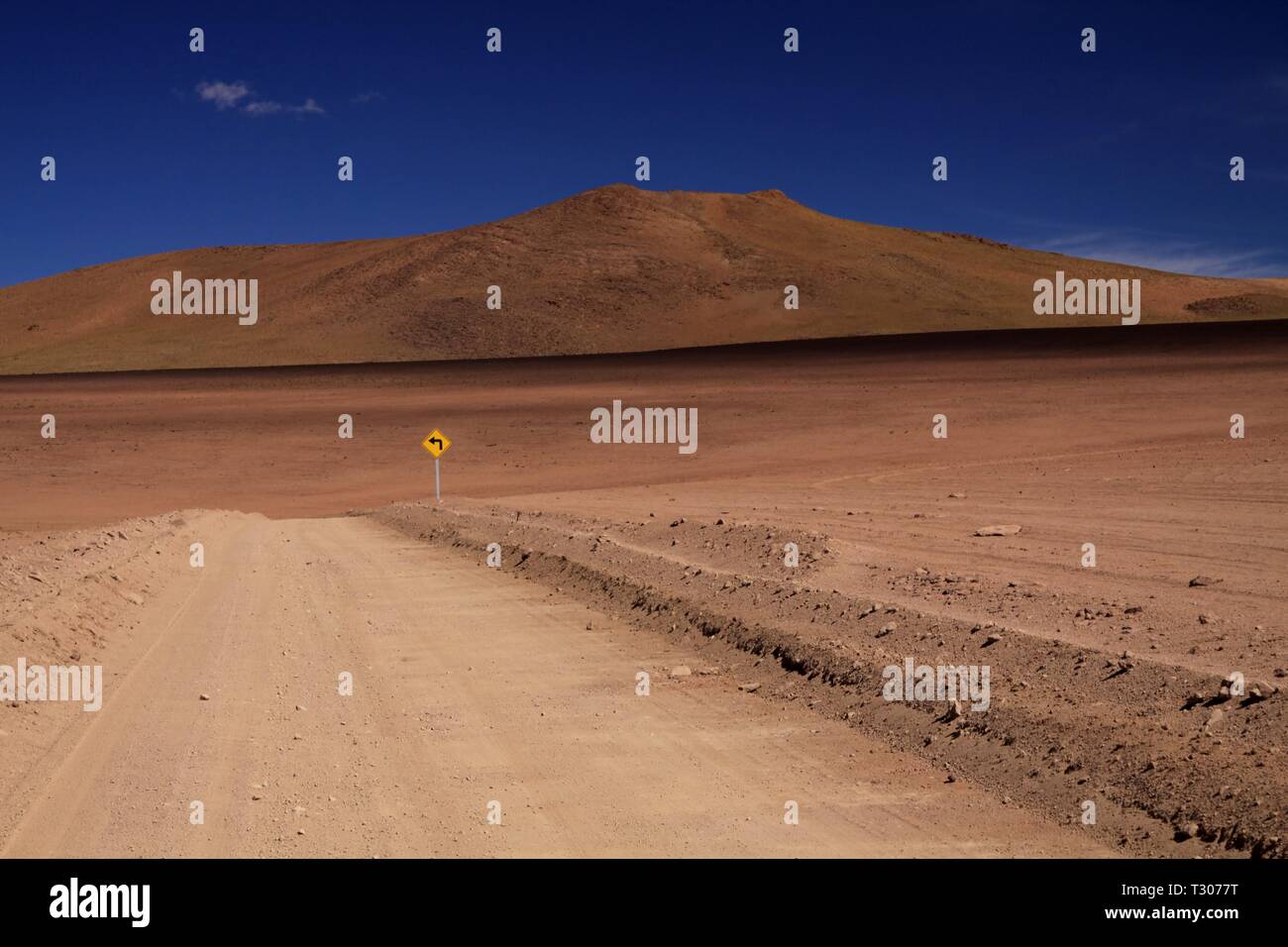 Dirt road through red wasteland contrasting with deep blue cloudless ...