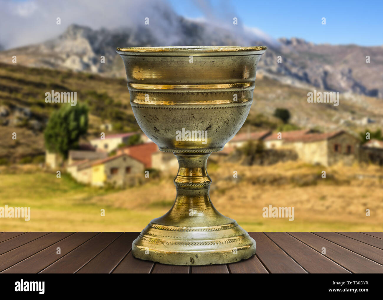 Old chalice on wooden table with a village in the background Stock ...