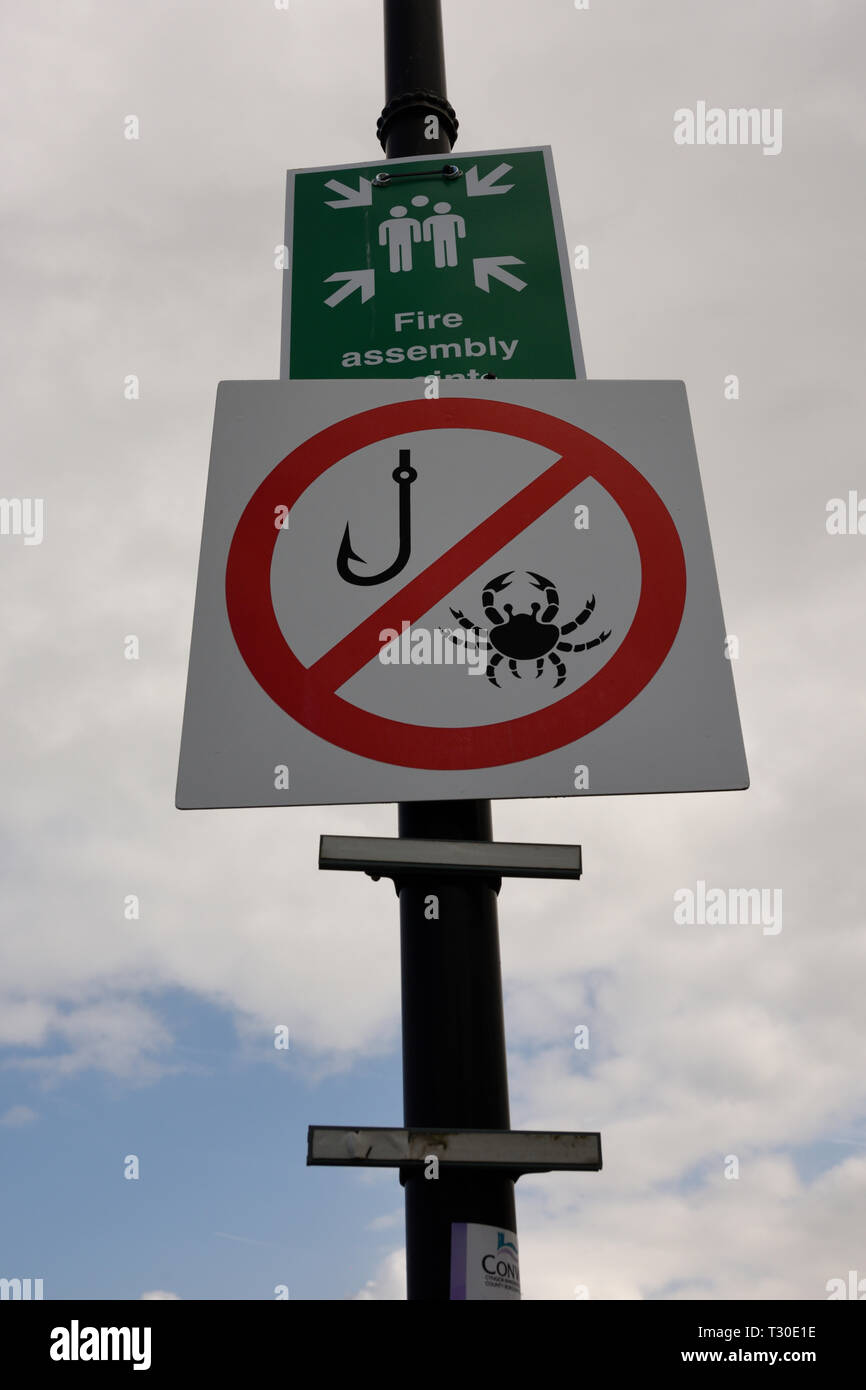 No crab fishing sign and fire assembly point sign on pole on Conwy ...